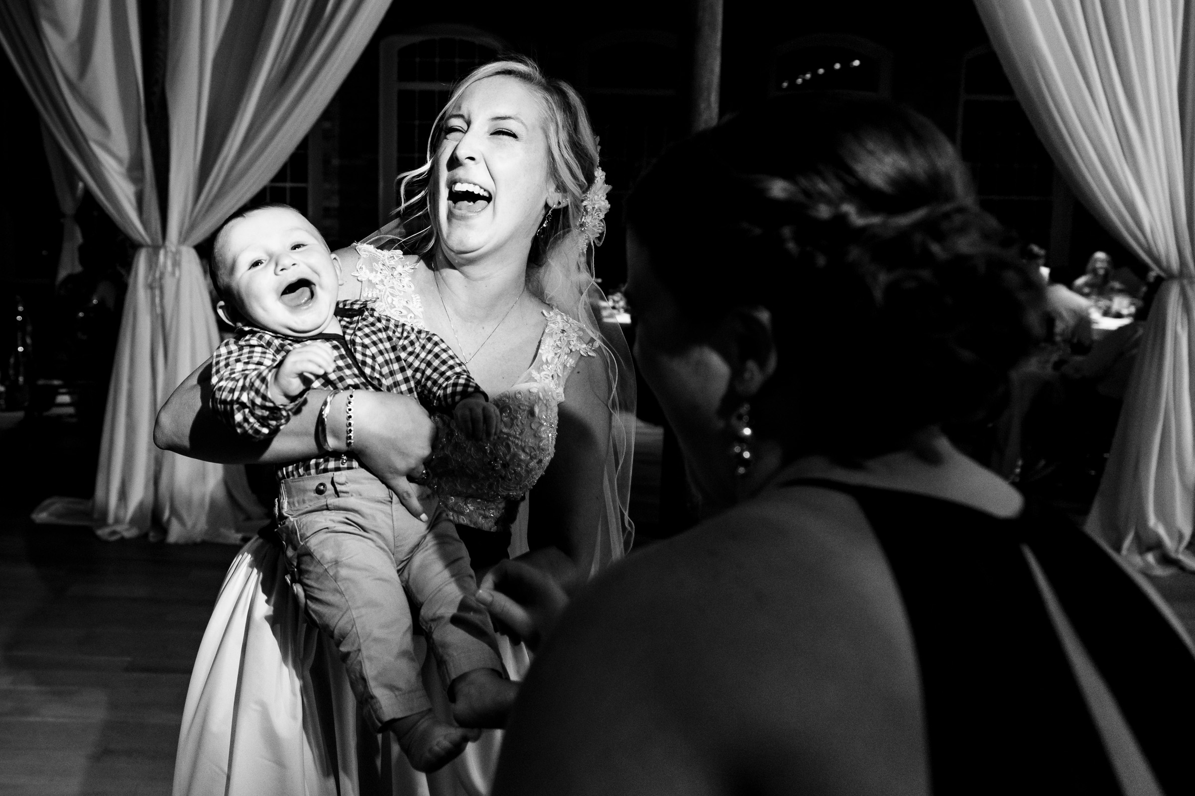 Bride holding laughing toddler - photo by Kivus & Camera