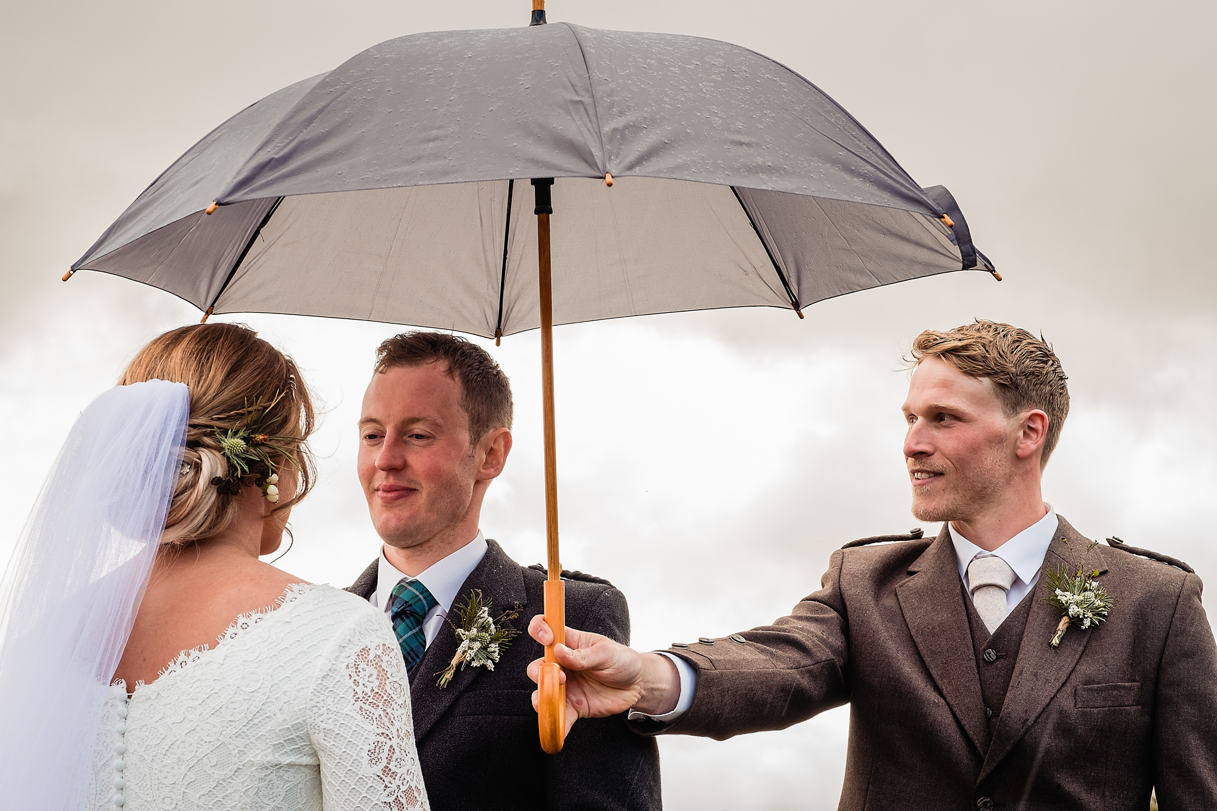 Groom faces bride under umbrella - photo by Emma + Rich