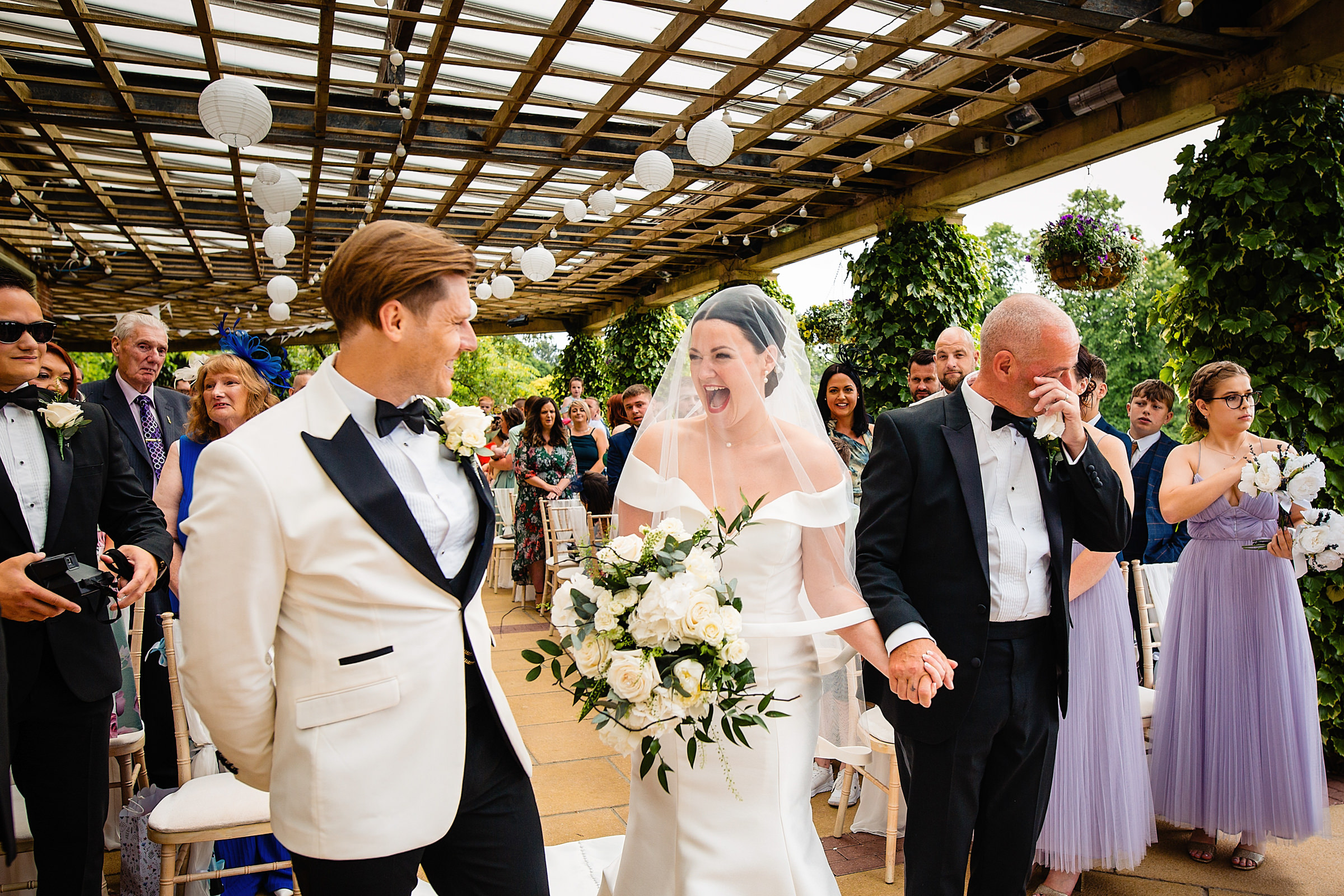 Emotional ceremony shot where father wipes a tear and bride greets ...