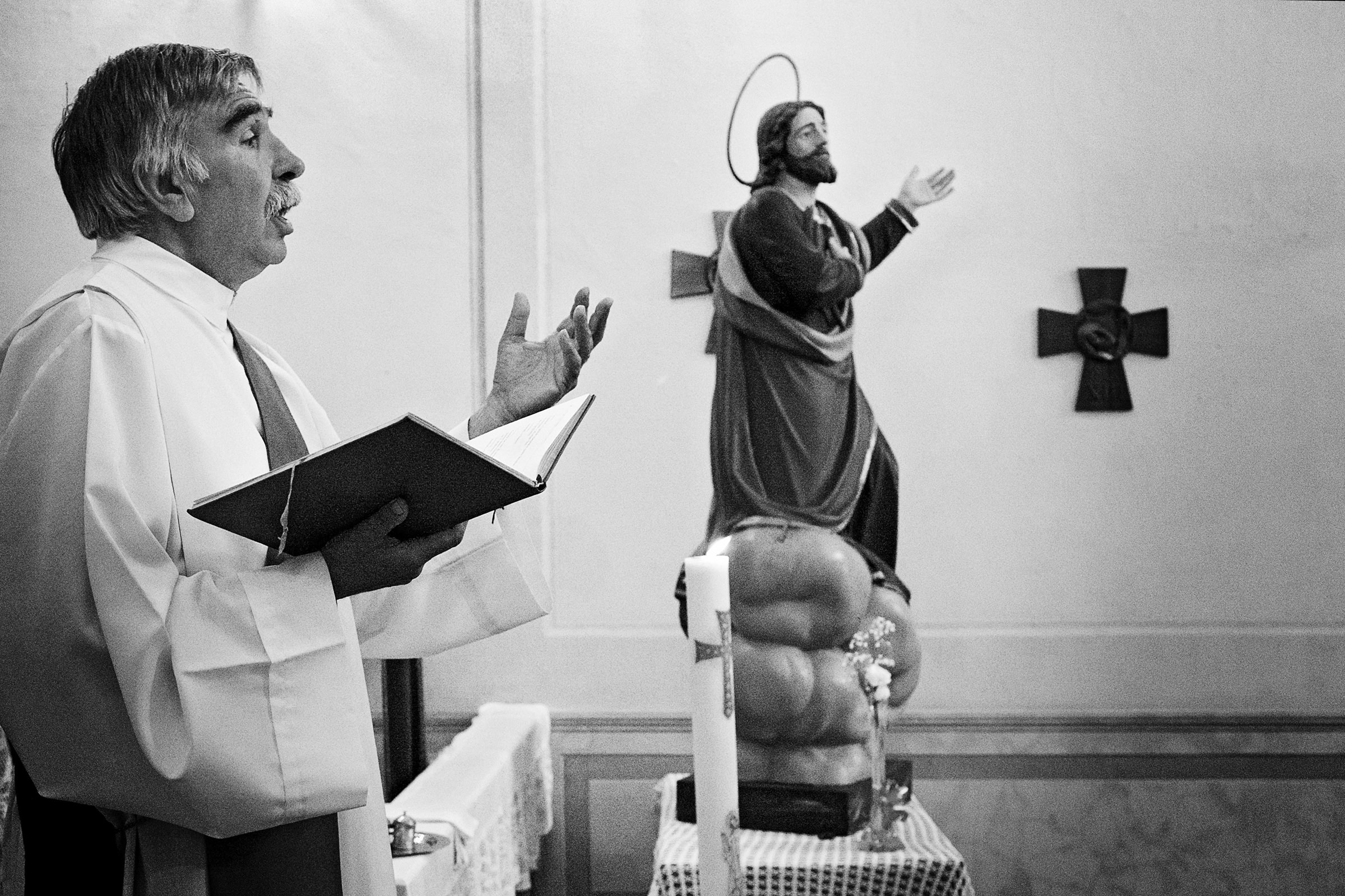 Priest mimicking pose of Jesus statue during ceremony - photo by Andrea ...